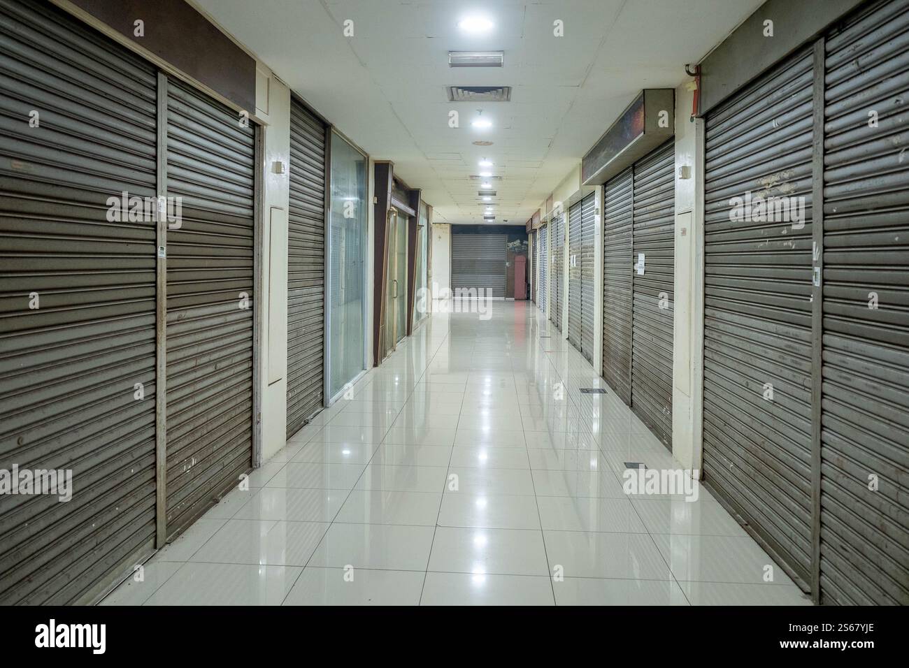 Metal roller shutters rolled down infront of shops inside an old mall ...