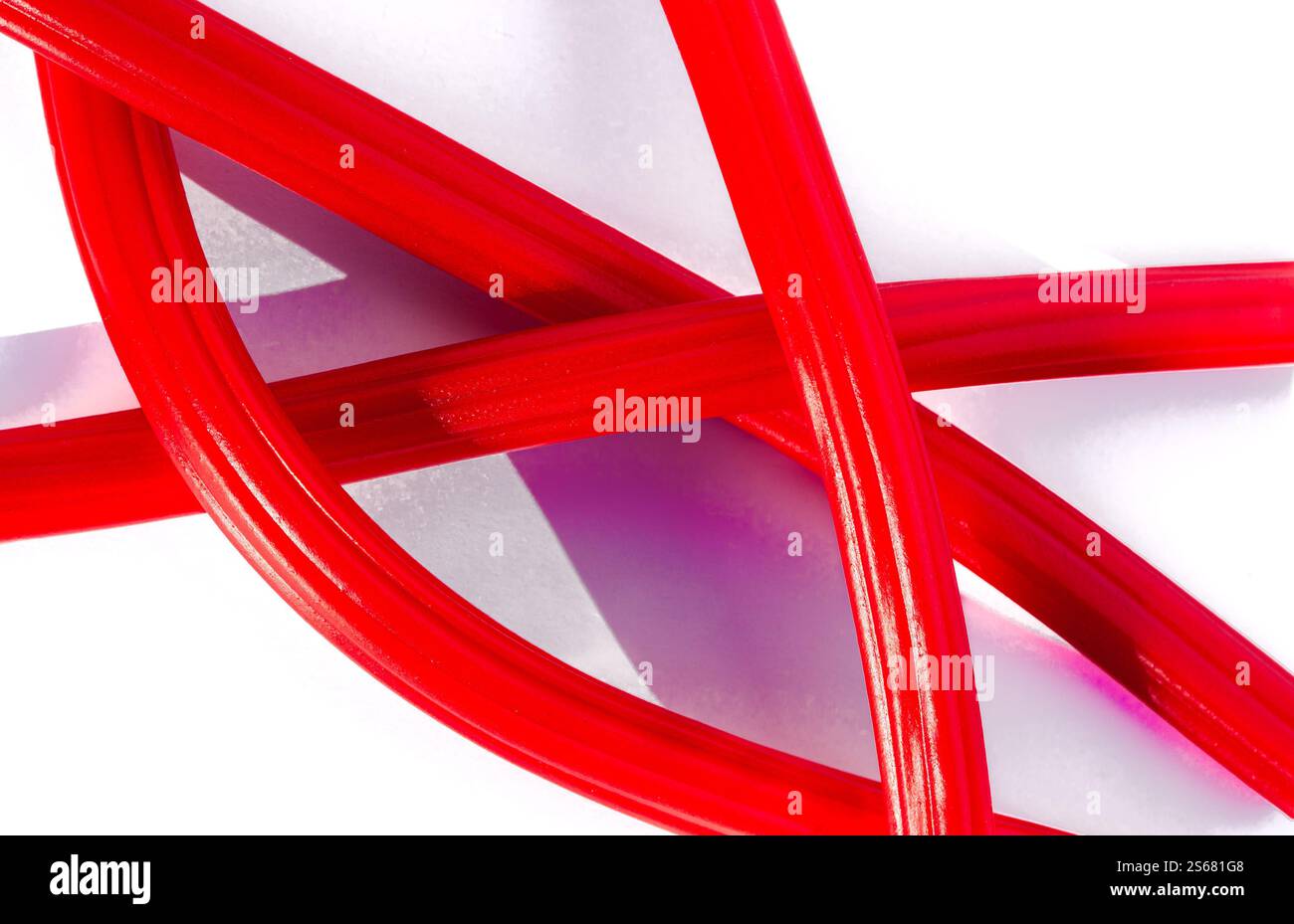Multiple intertwined red licorice sticks creating a pattern on white ...