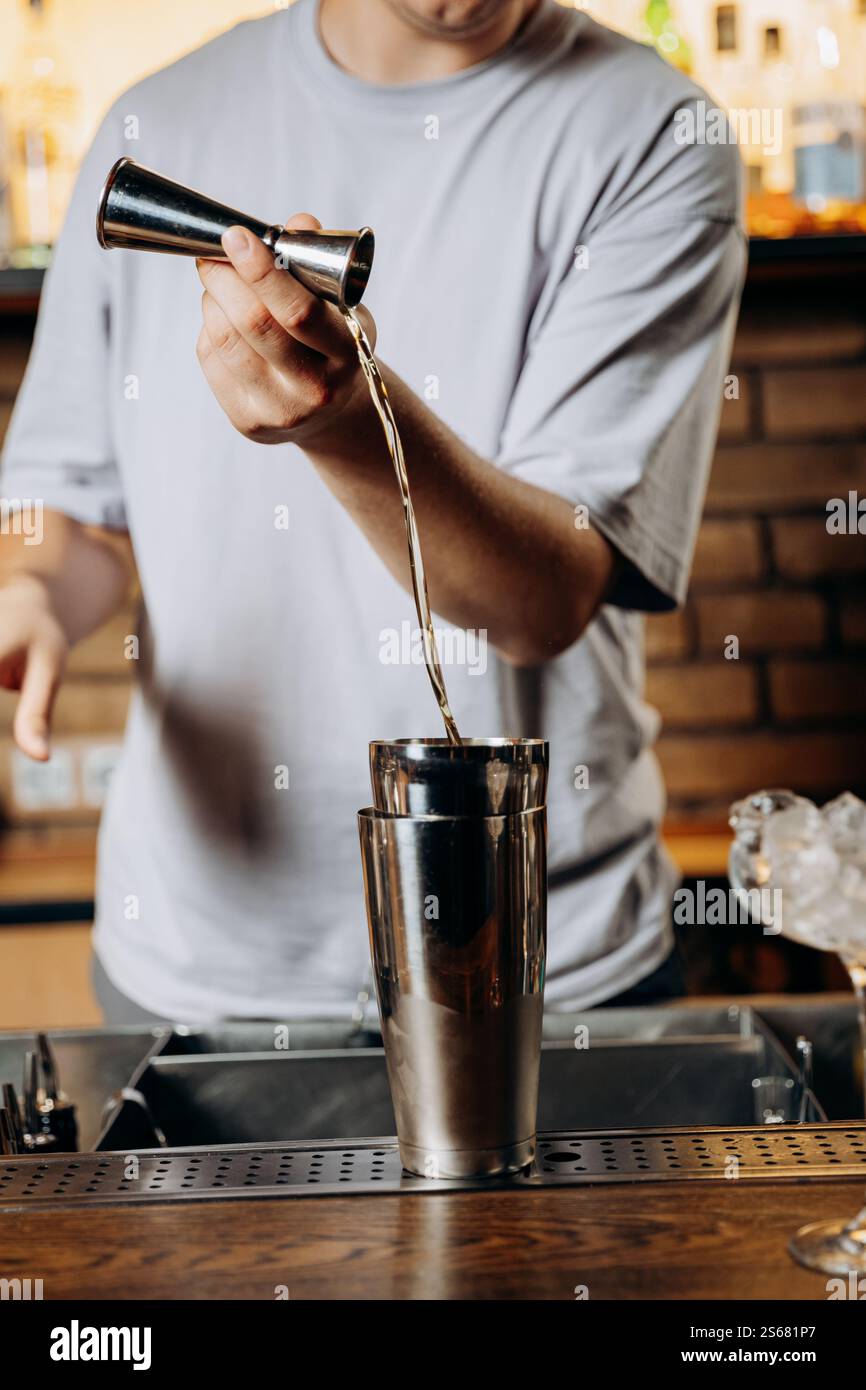 Bartender pouring liquor into a shaker, showcasing precision and craft in cocktail preparation ...