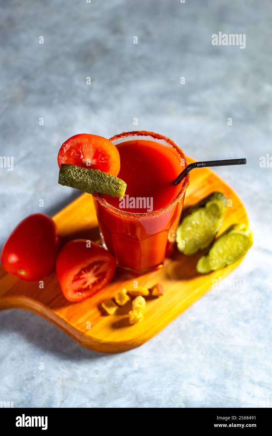 Bloody Mary cocktail in glass served with tomatoes and pickles on grey ...