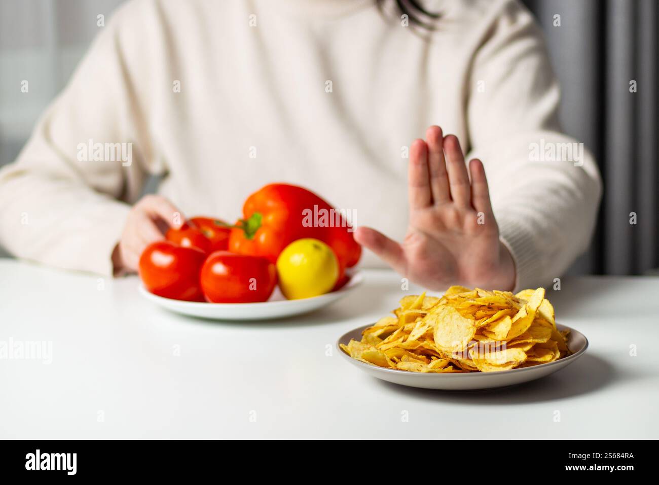 Woman saying "NO" to chips. Hand sign to refuse junk food. Choosing ...