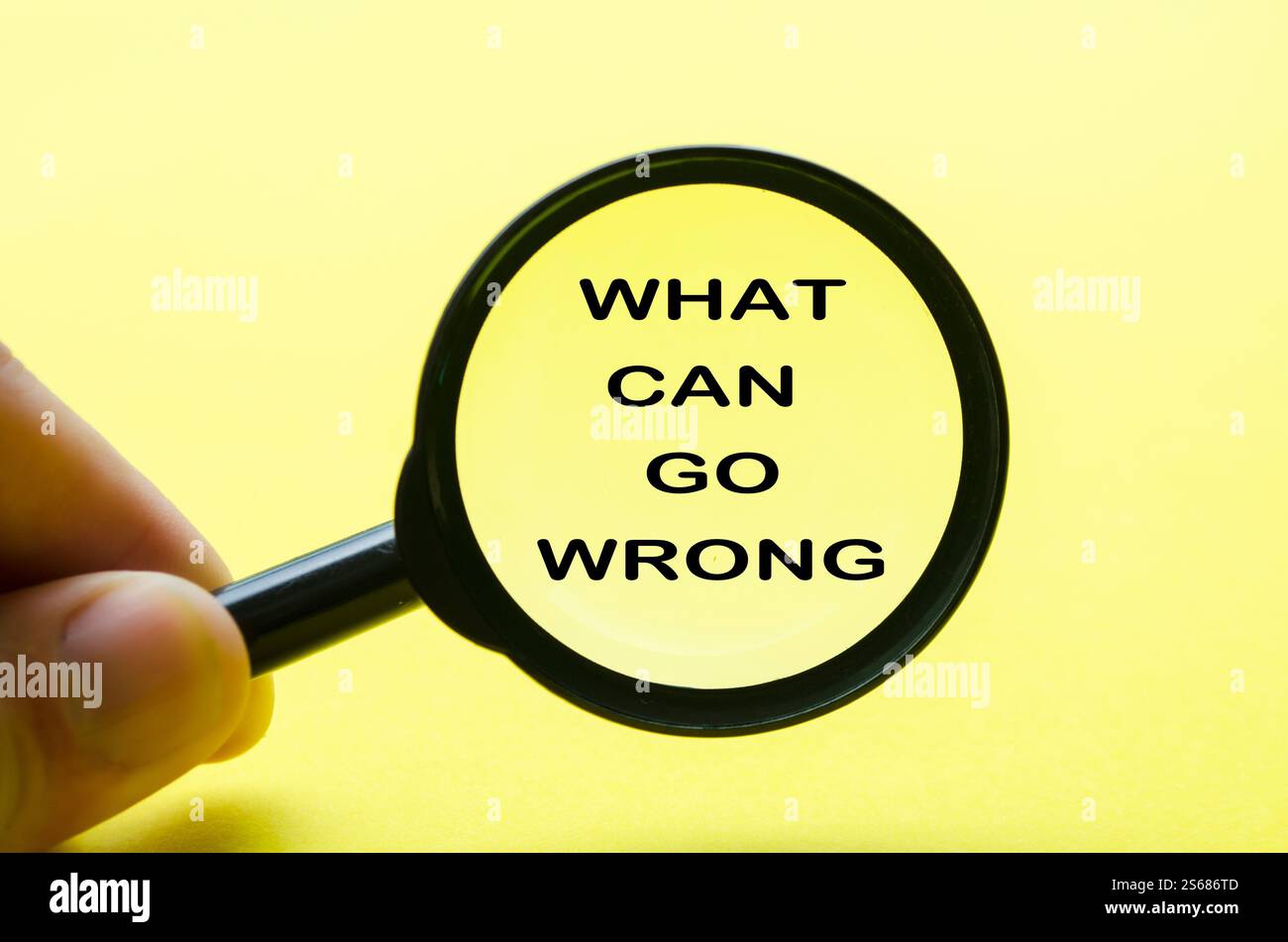 Hand holding magnifying glass with text what can go wrong. Fact finding ...