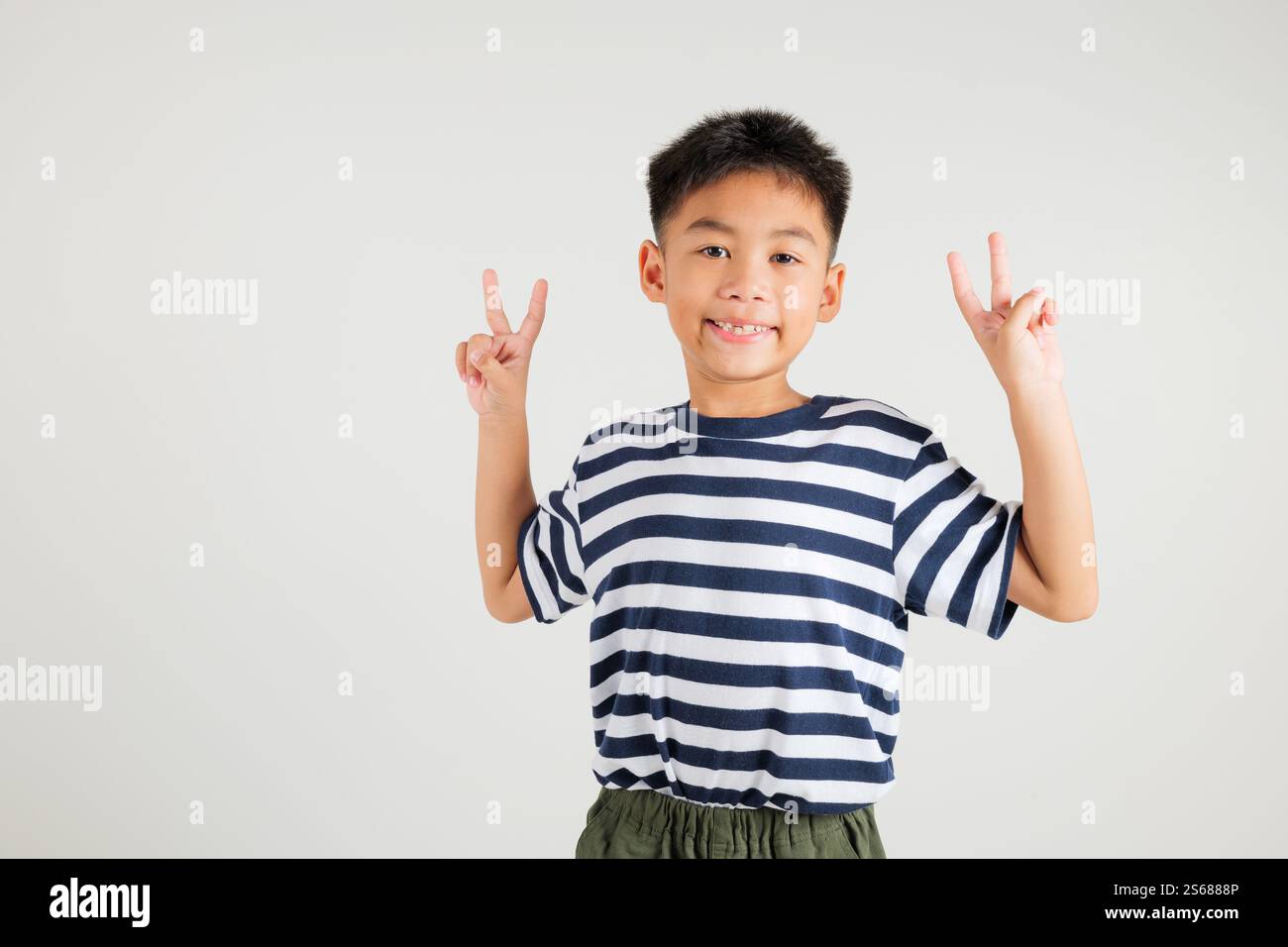 Asian young kid boy showcases optimism and peace by gesturing victory ...