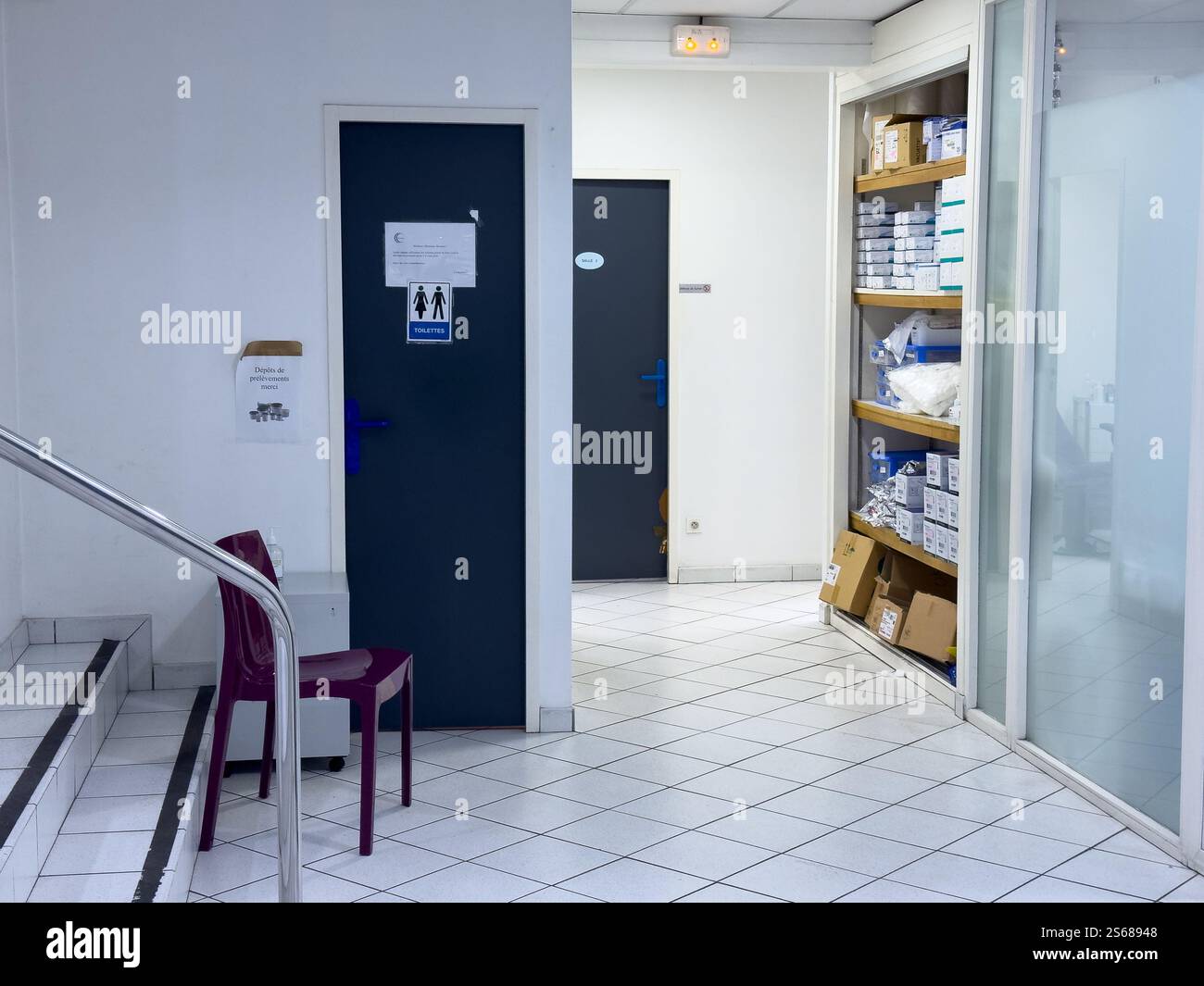 Quiet hallway in a medical facility with storage and restroom signage ...