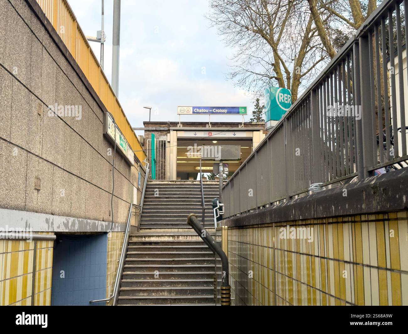 Busy urban subway entrance with stairs and signage on a cloudy day ...
