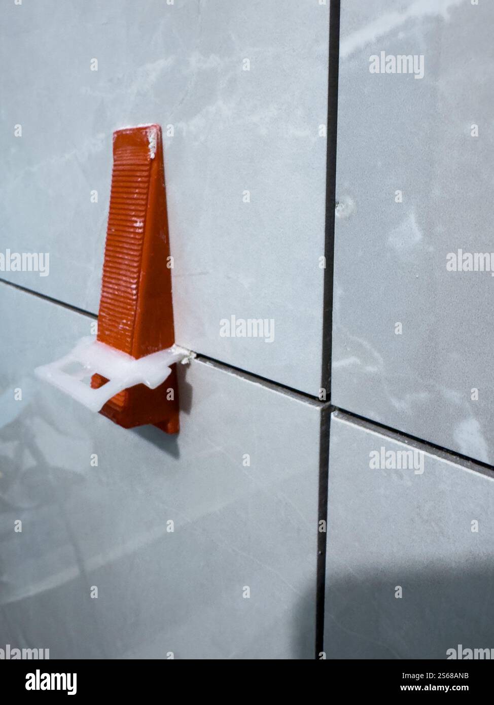 Tile spacer positioned between ceramic tiles on a wall during ...