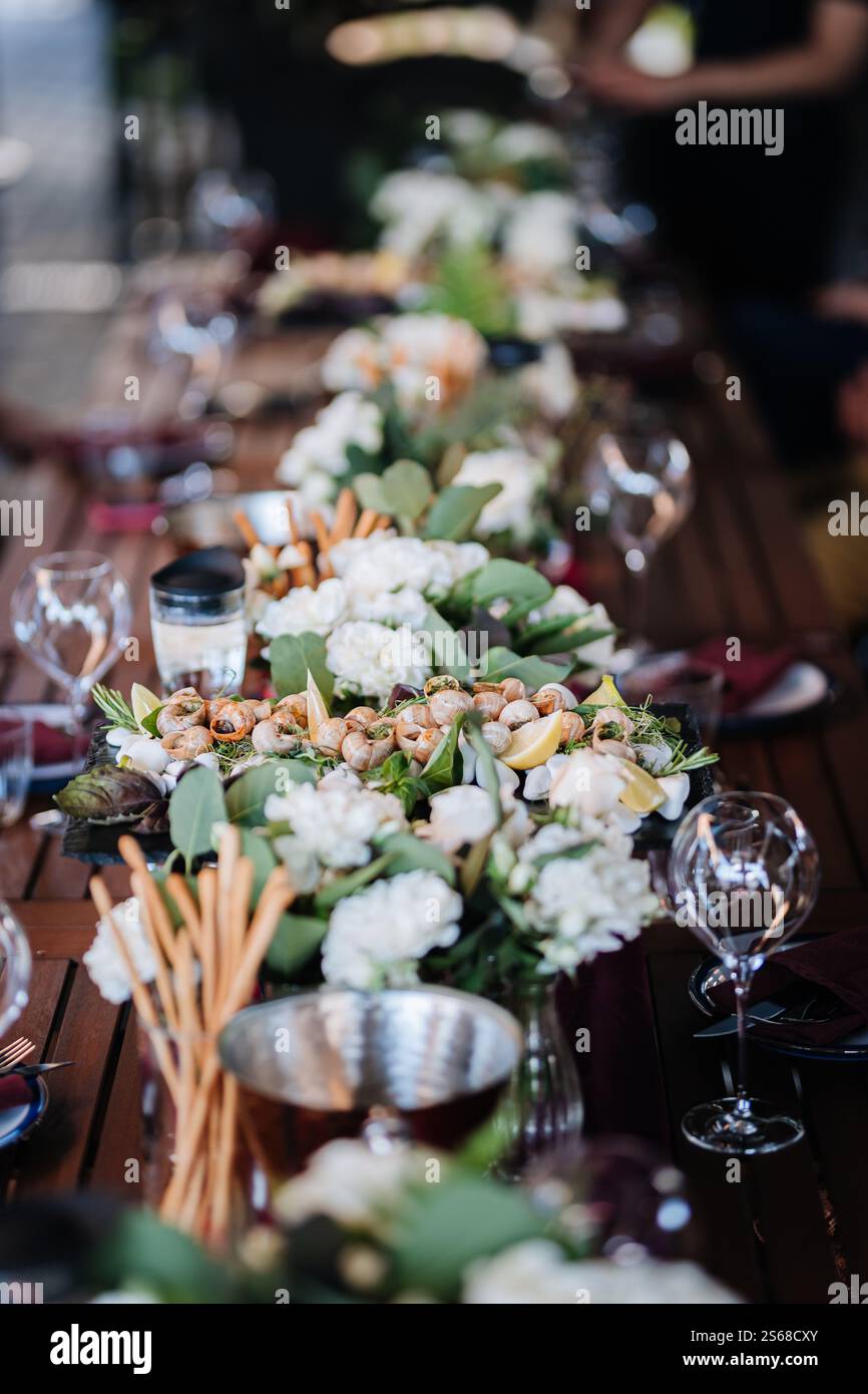 Luxurious dining table setup with flowers, appetizers, and wine glasses for an elegant ...