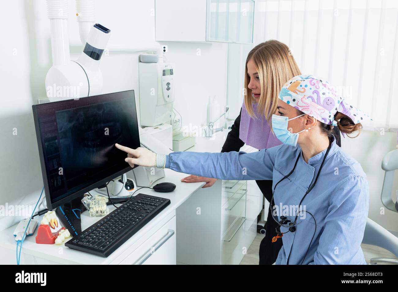 Dentist pointing at teeth x ray on computer screen, explaining ...