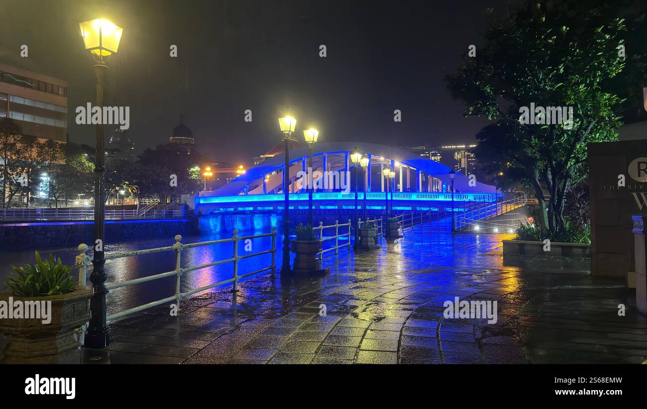 Wet pavement and bridge along the Singapore River in the Boat Quay area ...
