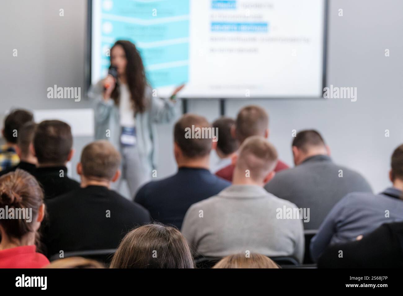 Female presenter engaging audience during business conference with ...
