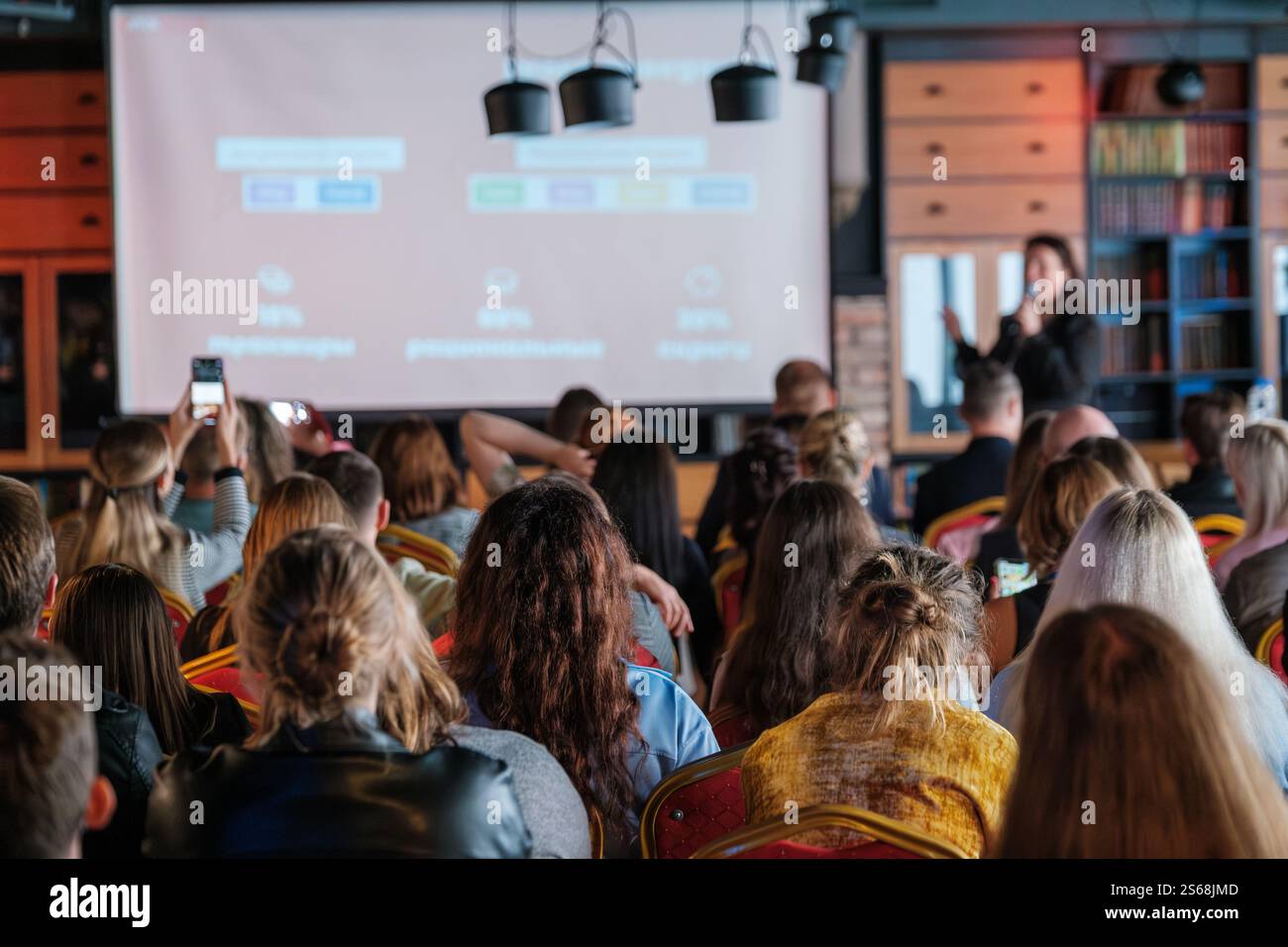 Audience members seated in a conference room listening to a speaker ...