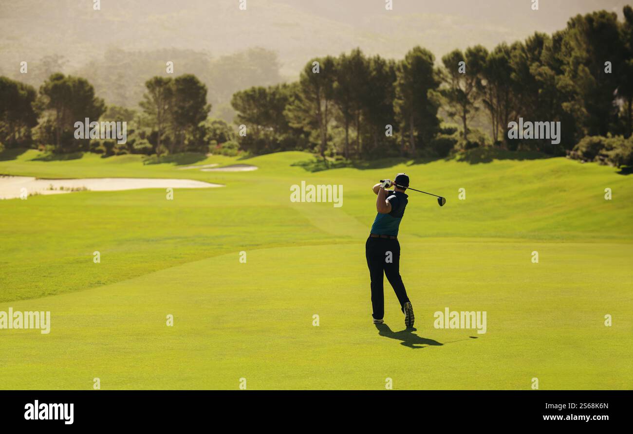 Golfer executing a powerful swing with great follow through on a lush ...