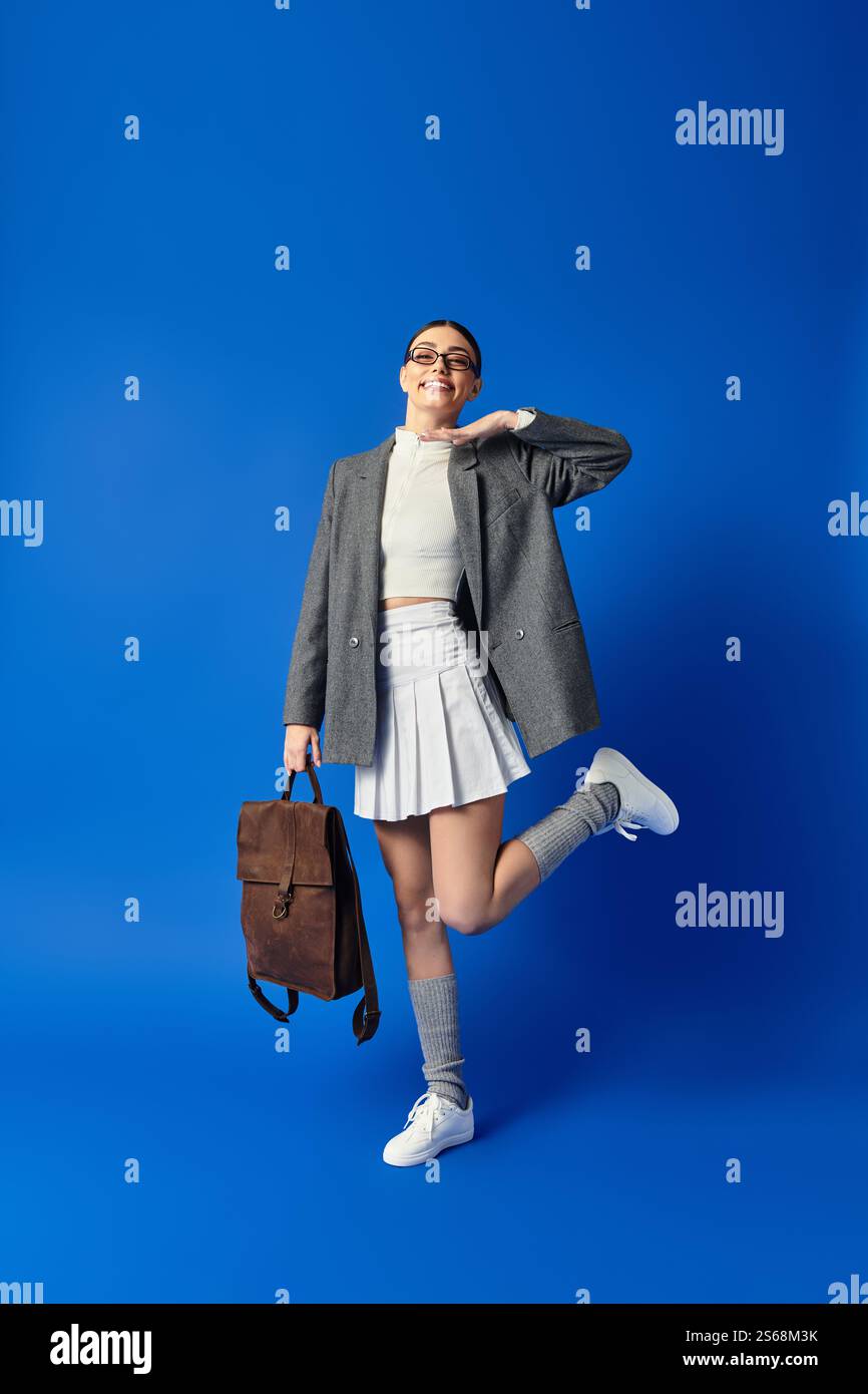 A joyful young woman strikes a playful pose while holding a backpack ...
