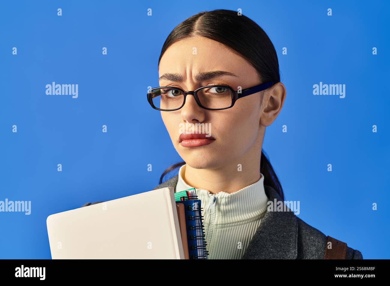 A beautiful young woman stands confidently holding notebooks ...