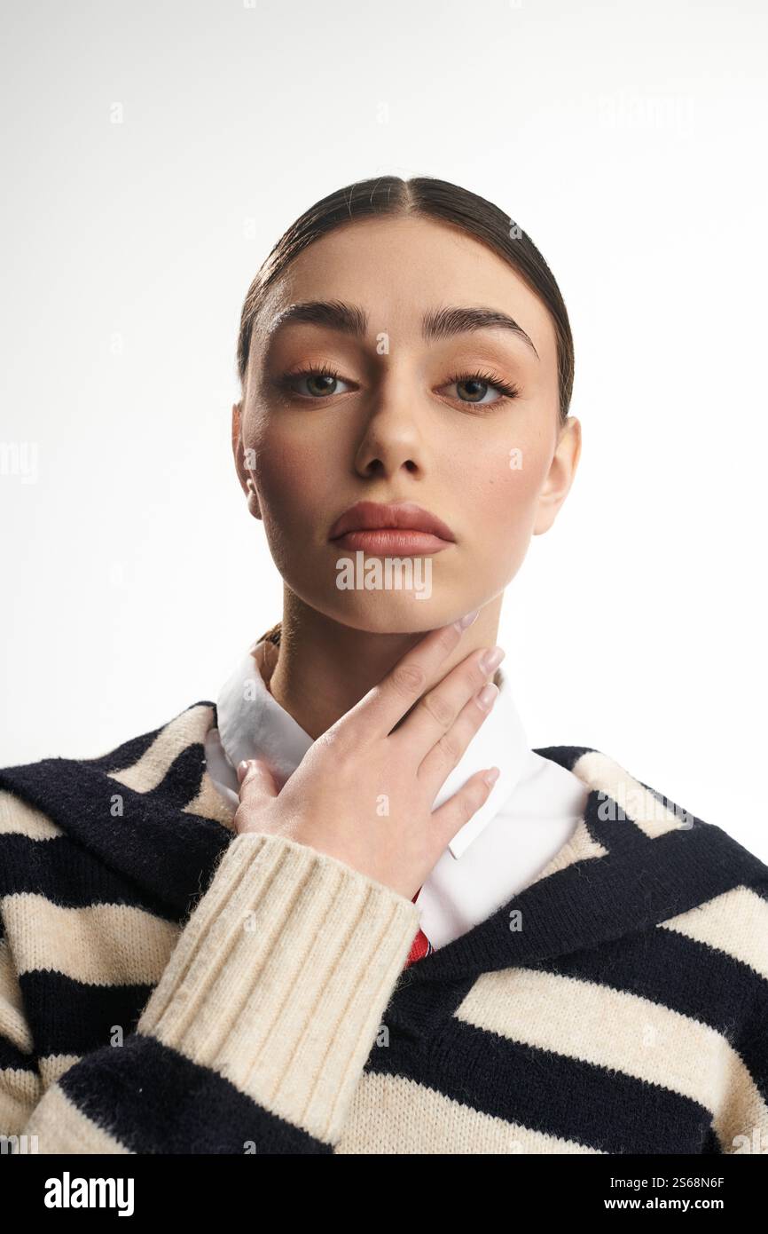A young woman gazes thoughtfully while touching her neck, showcasing ...