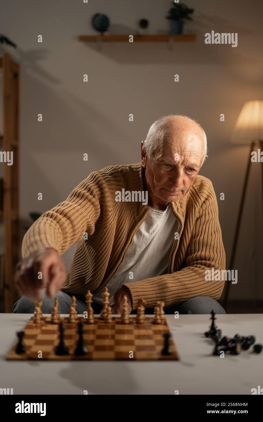 Retired senior concentrates on chess moves, engaging in mentally ...