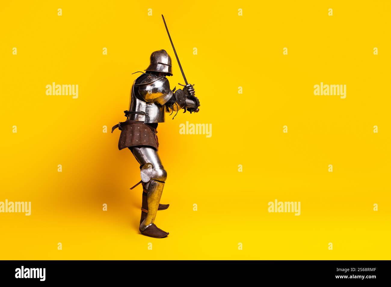 Medieval Knight in Steel Armor Posing with Sword Against Vibrant Yellow ...