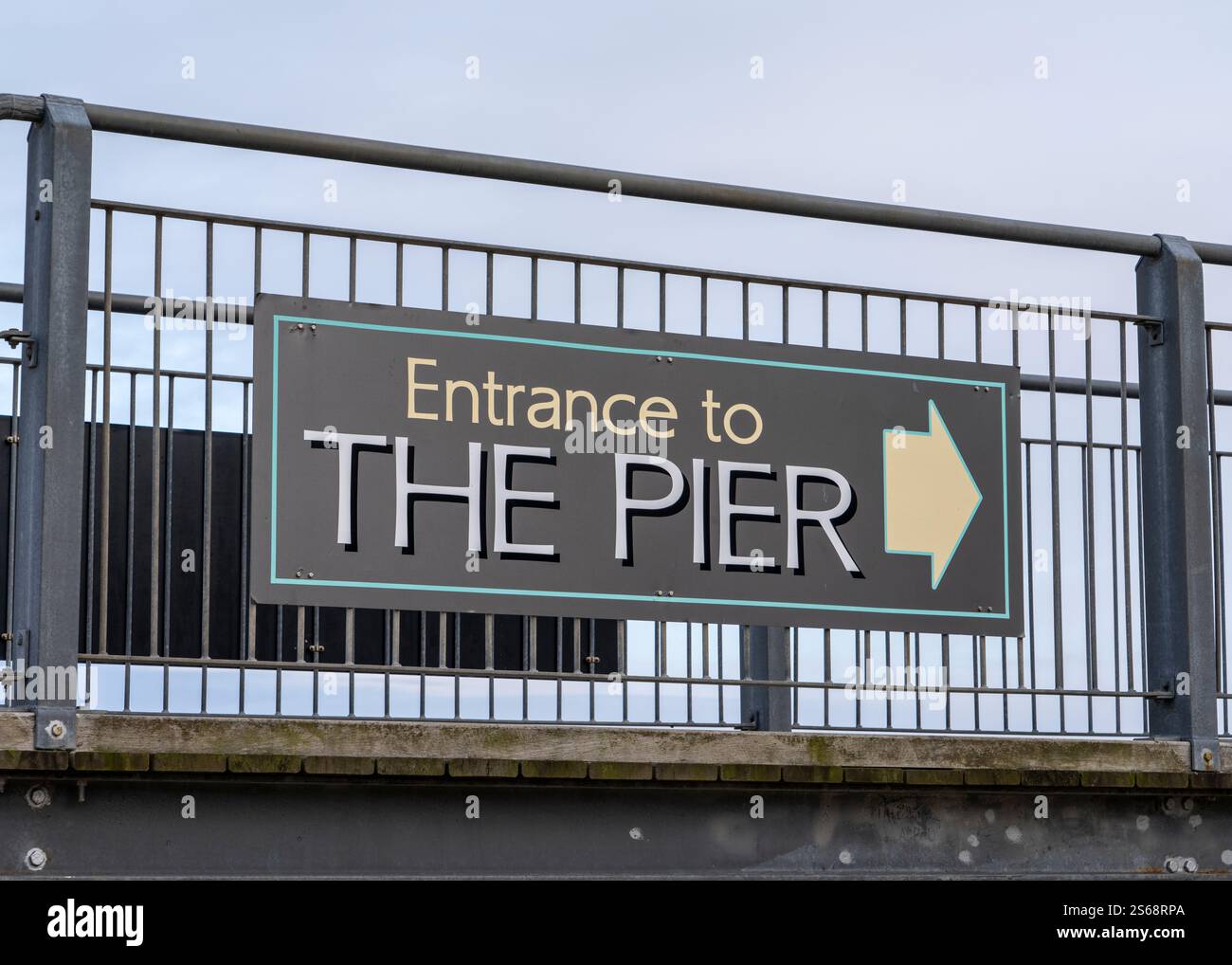 Sign stating “Entrance to The Pier” attached to railings at a coastal ...