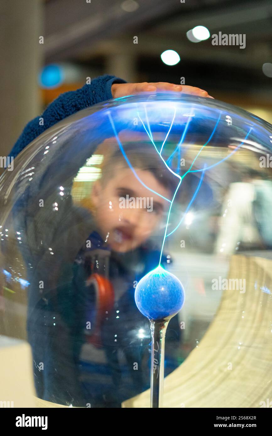 Young boy touching plasma globe, experiencing the wonders of static ...