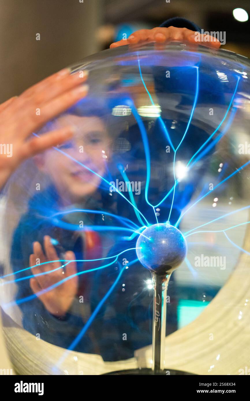 Curious child and adult exploring a plasma ball exhibit, learning about ...