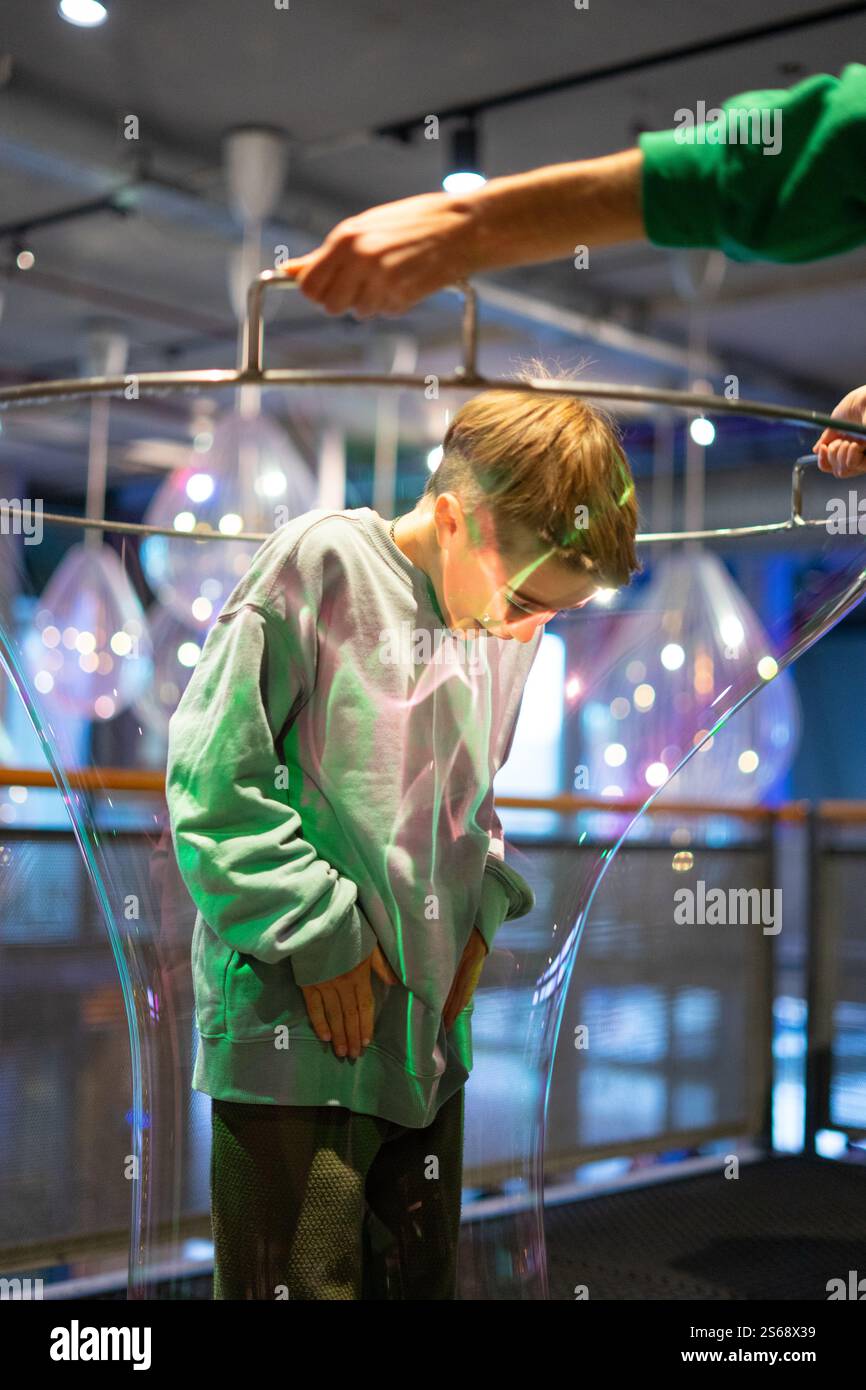 Curious child exploring giant soap bubble during interactive science ...