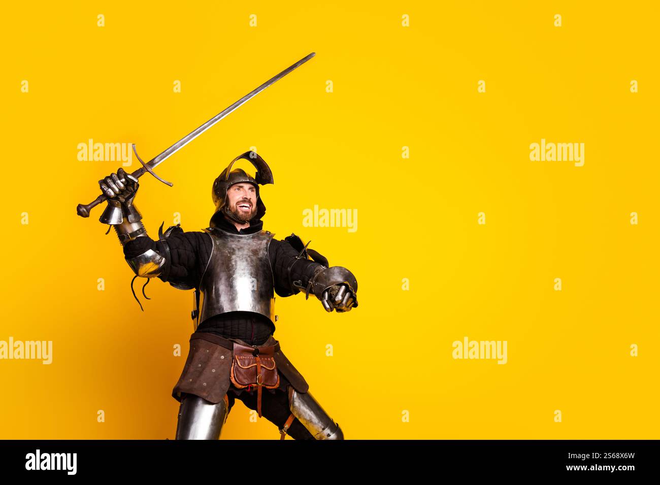 Knight in medieval armor posing with sword on vibrant yellow background ...