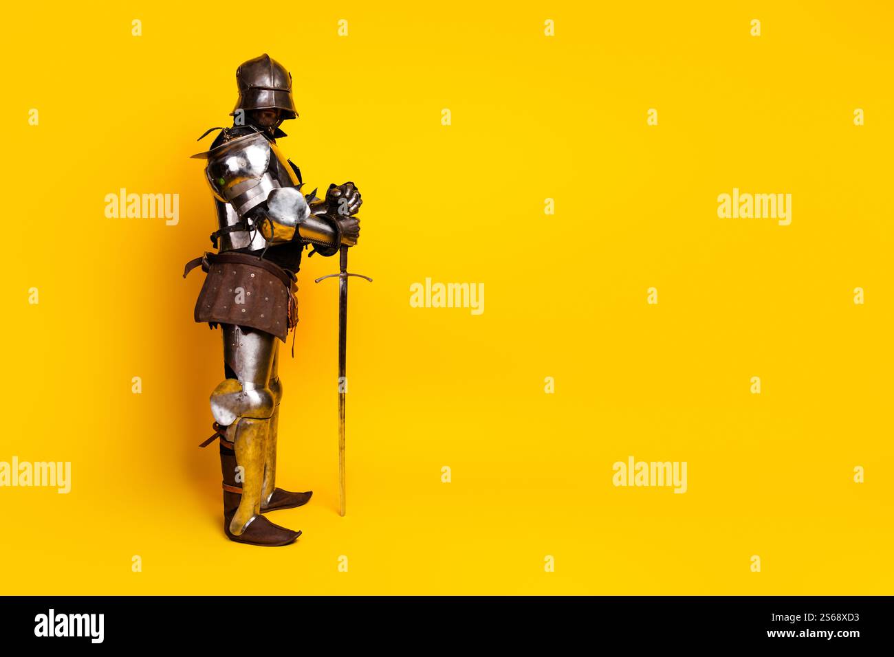 Medieval knight in armor with sword posing on yellow backdrop, blending ...