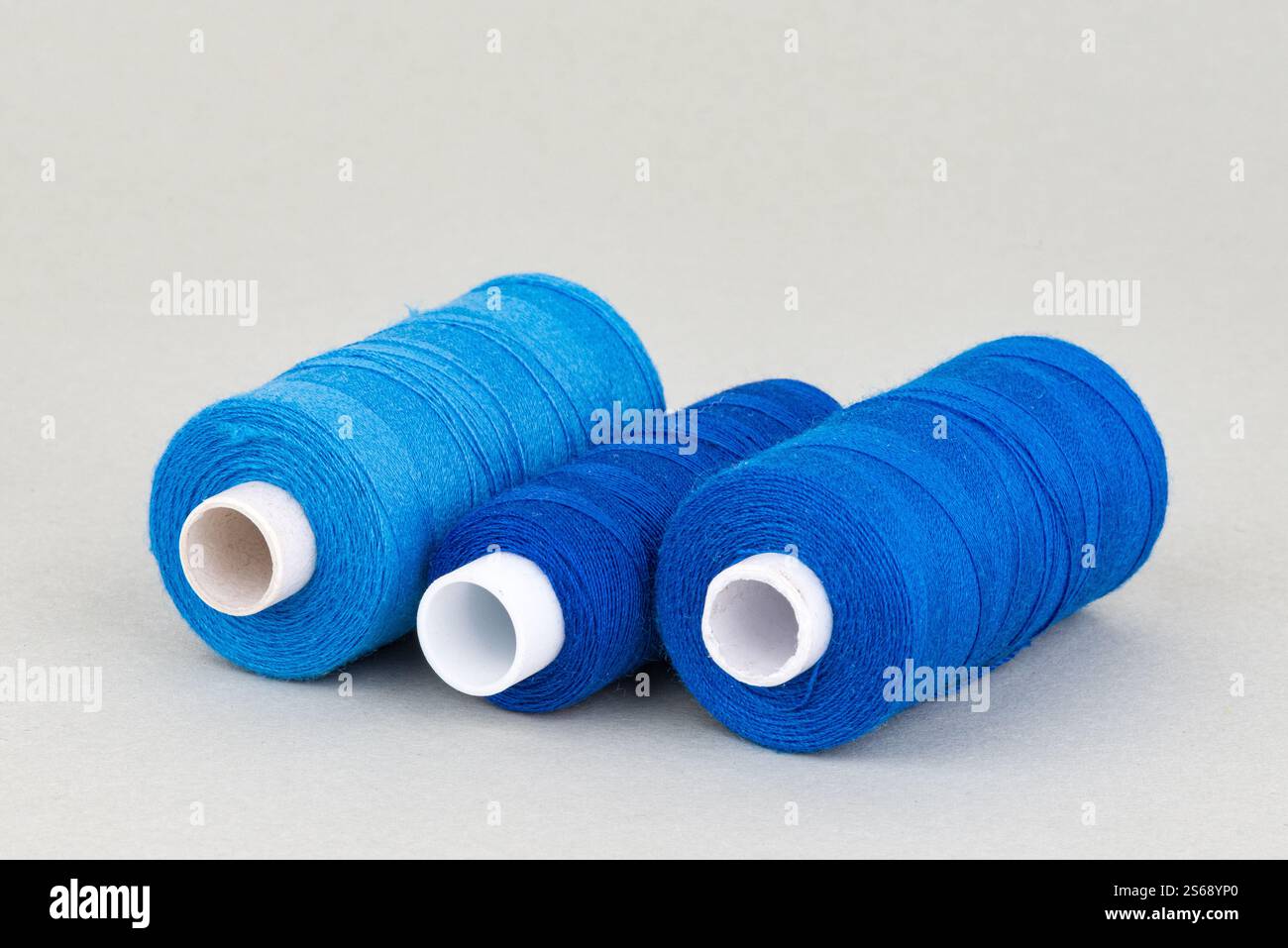 Blue thread spools on grey background Stock Photo - Alamy