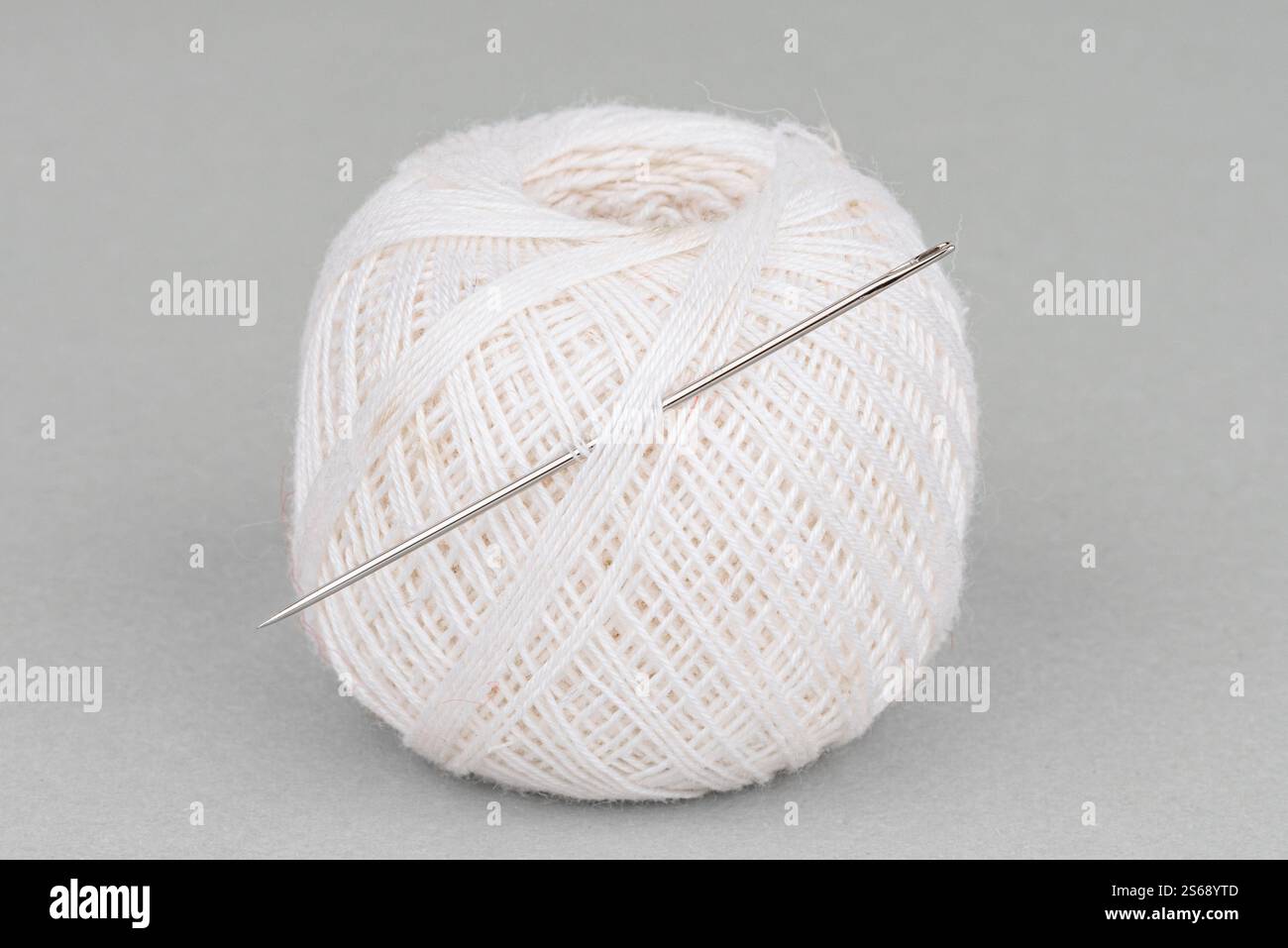 White thread spool with needle on grey background Stock Photo - Alamy