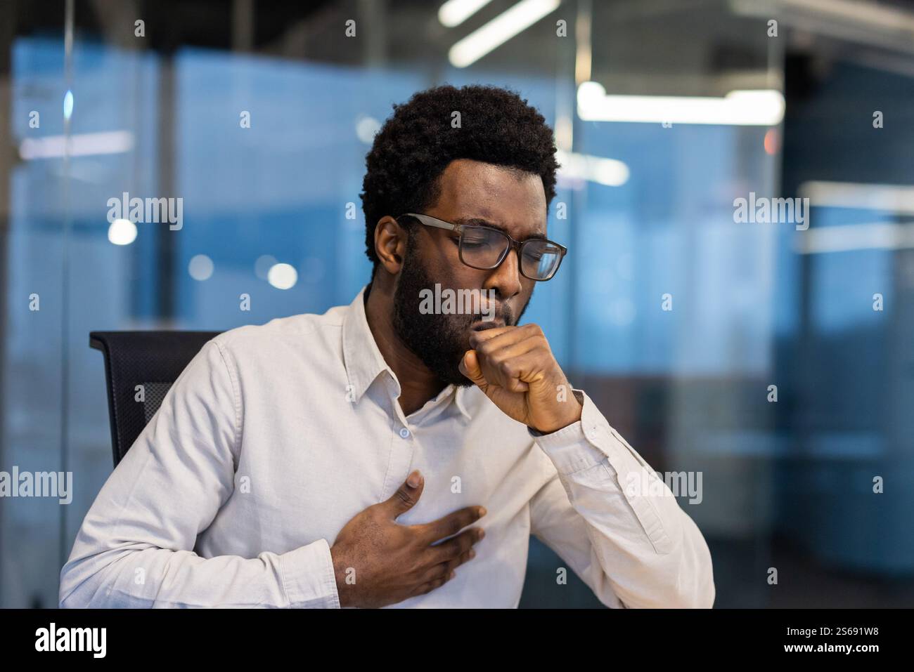 Cold and sick man at workplace inside office coughing, businessman ...