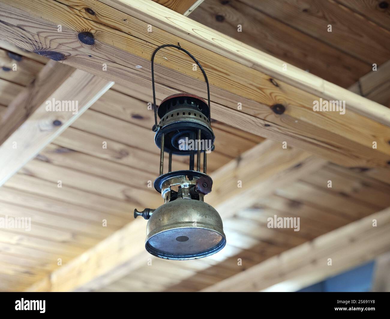 Vintage traditional antique incandescent oil lamp on a wooden ceiling ...