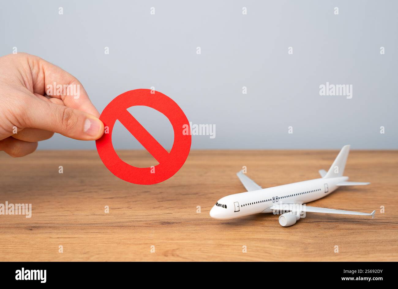 Hand holding a red NO sign near a passenger plane. Flight restrictions ...