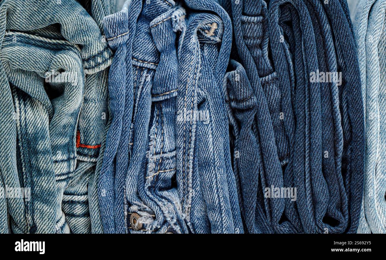 Different styles of denim jeans are neatly folded and organized by ...