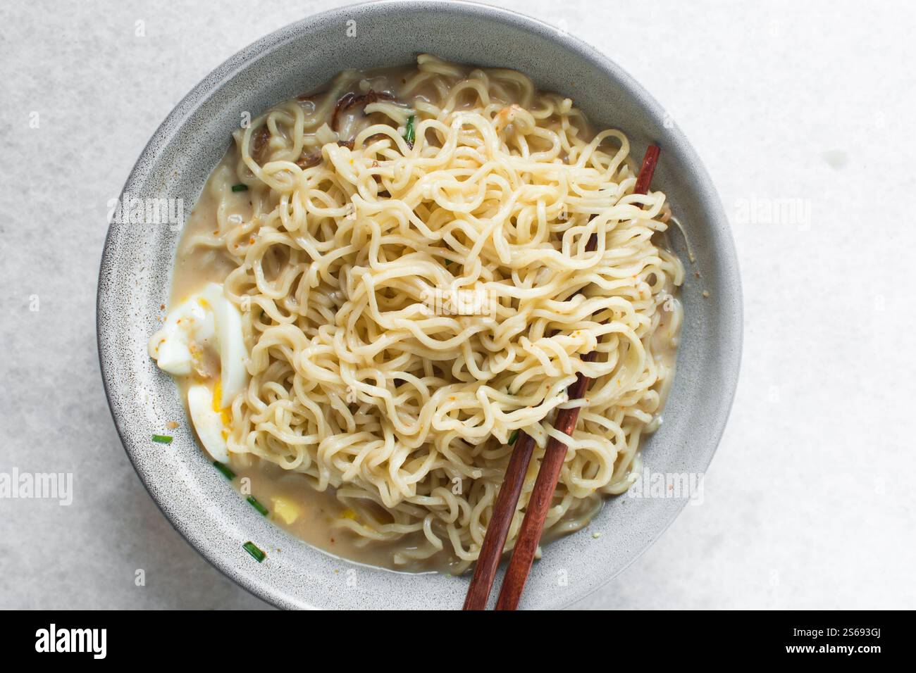 Overhead view of noodles in milk broth in a grey bowl, top view of ...
