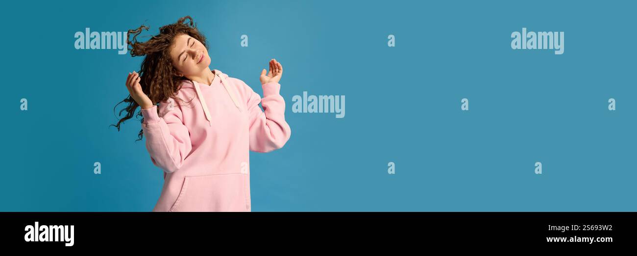 Carefree, calm young girl shaking her head of joy, hair flowing against ...