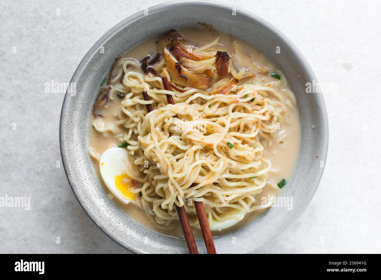 Overhead view of noodles in milk broth in a grey bowl, top view of ...