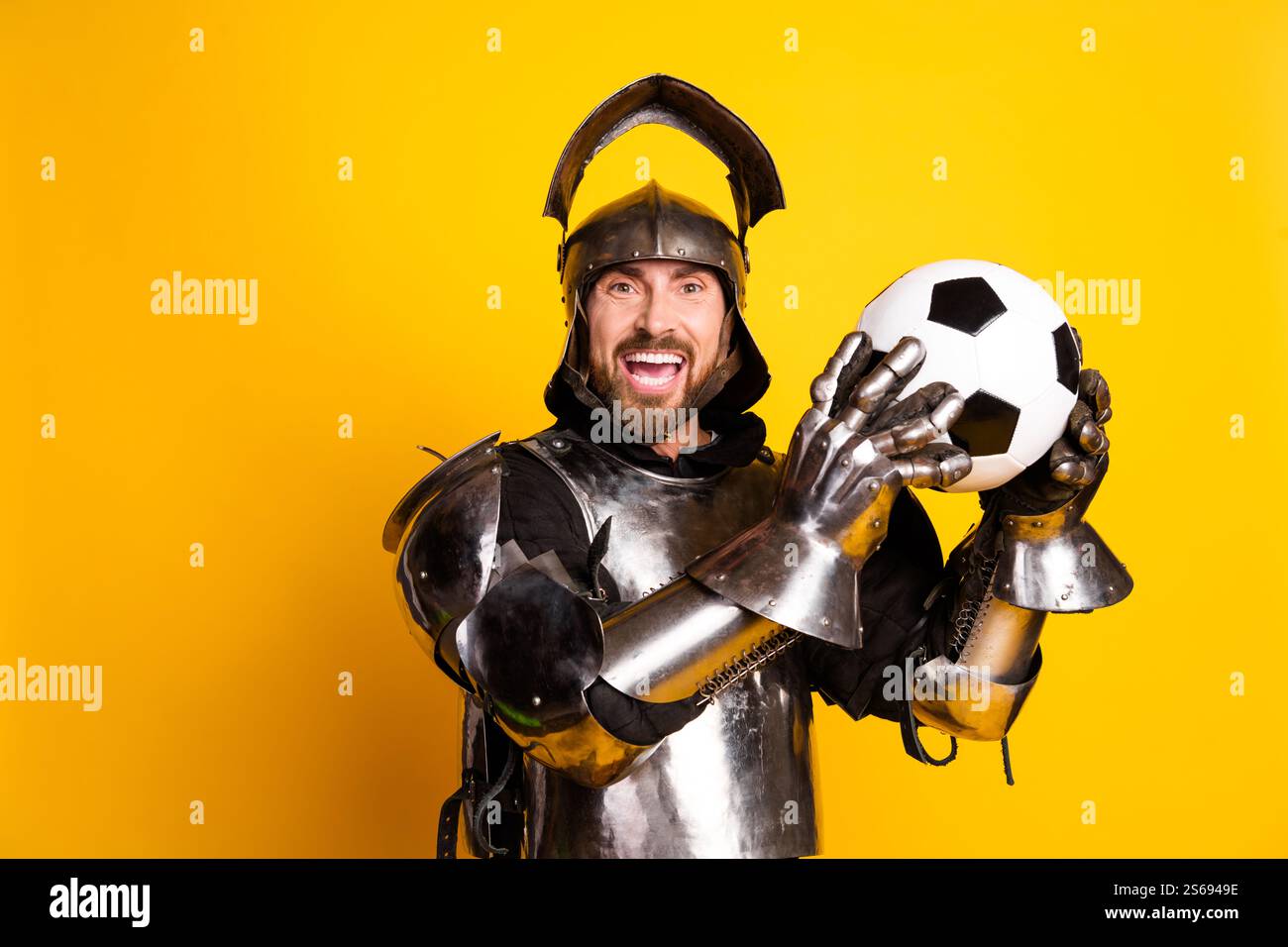 Medieval knight in full armor posing with a soccer ball against yellow ...