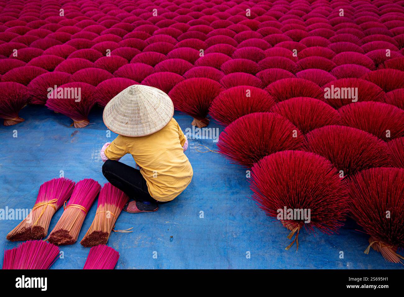 Aerial view of incense workers sits surrounded by thousands of incense ...