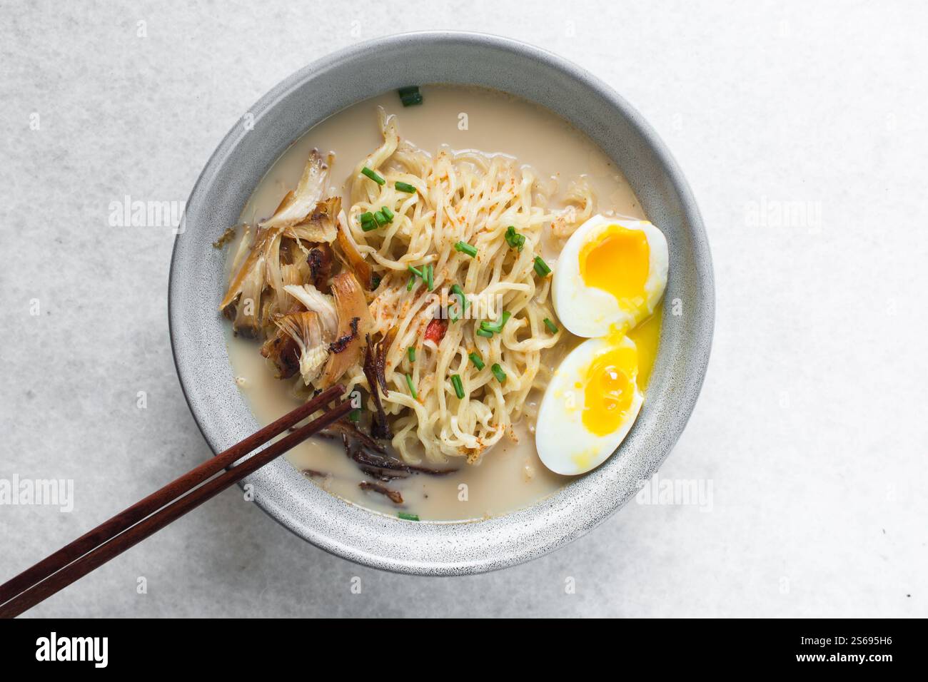 Overhead view of noodles in milk broth in a grey bowl, top view of ...