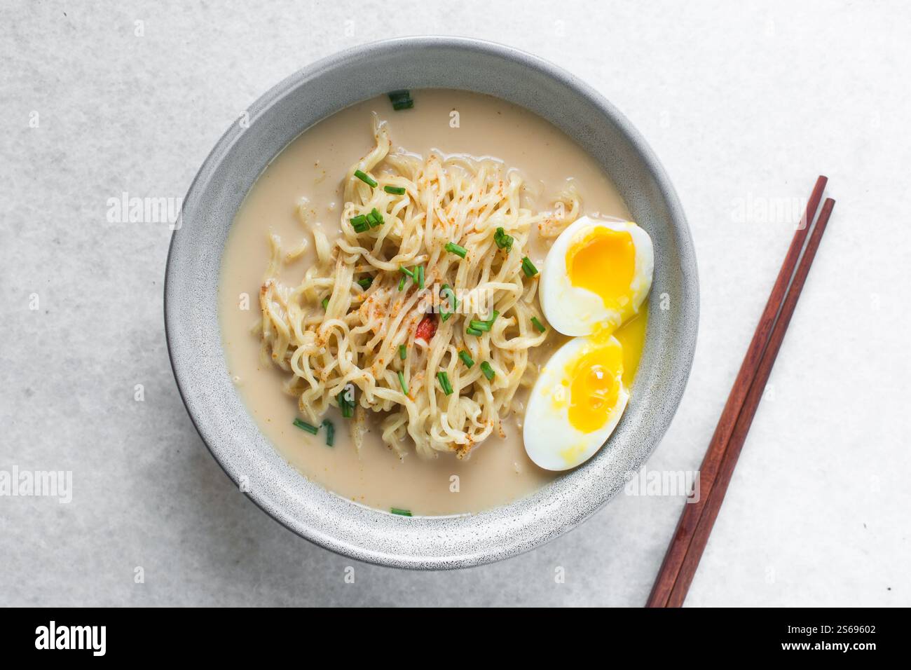 Overhead view of noodles in milk broth in a grey bowl, top view of ...