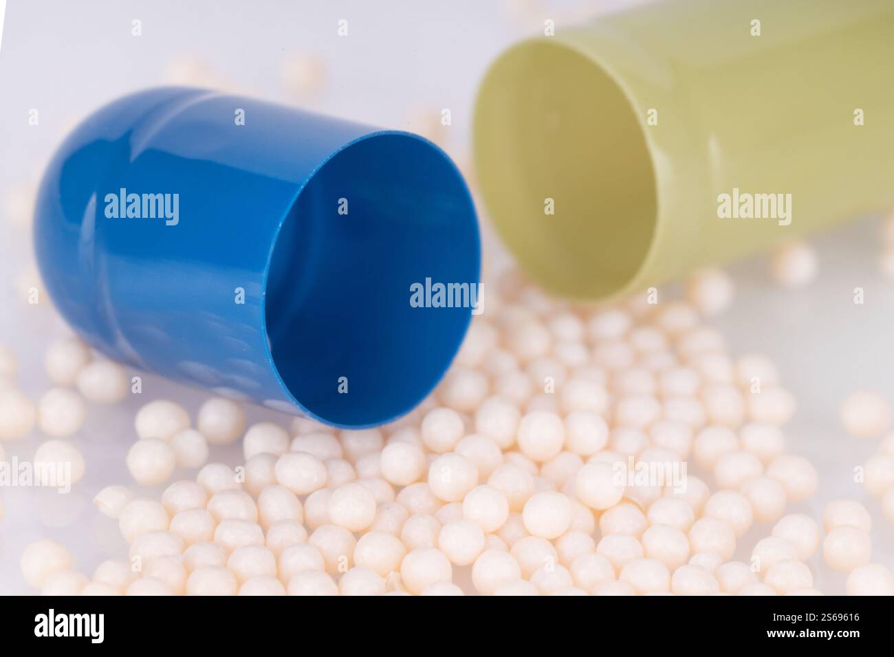 Split medical capsule with scattered granules Stock Photo - Alamy