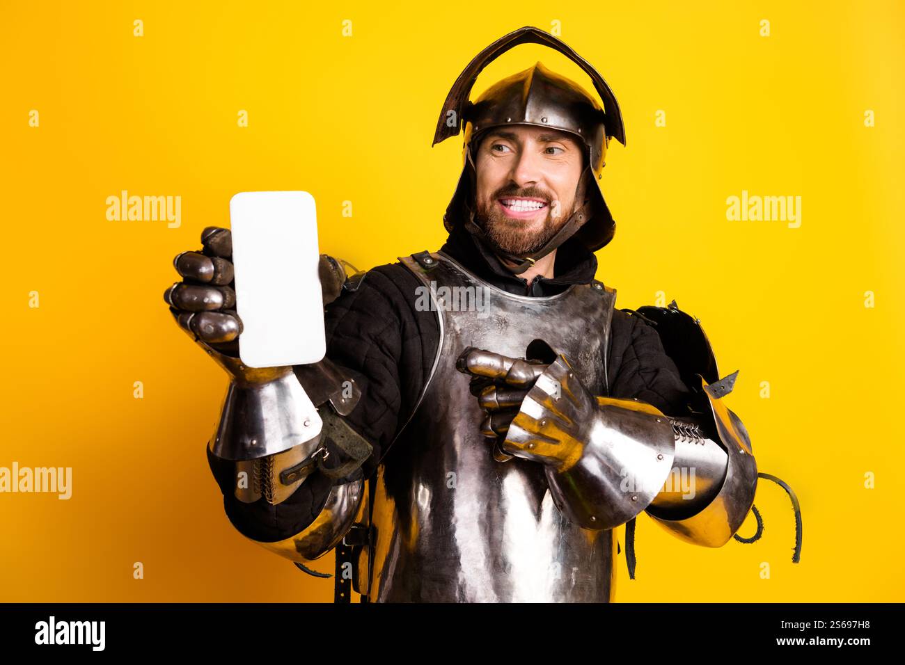 Smiling knight wearing armor holding smartphone with a yellow ...