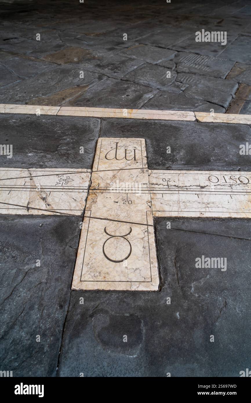 A detailed close-up of a marble sundial inlaid in the ground, featuring ...
