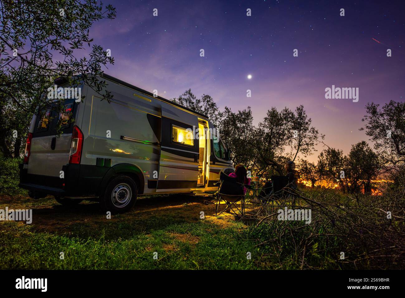 Night photo of campervan or motorhome parked in an olive grove garden ...