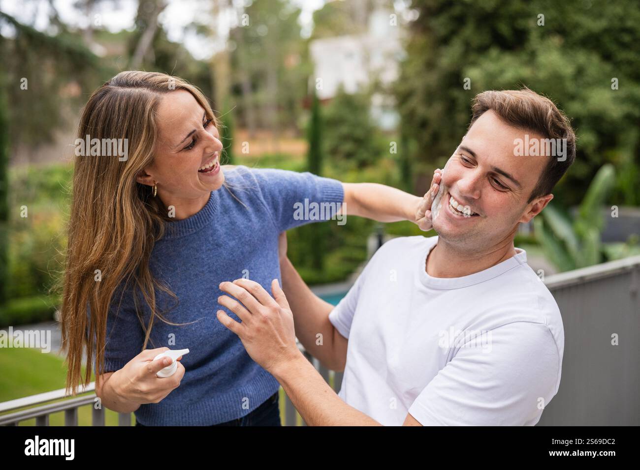 Playful couple applying sunscreen or exfoliating cream on balcony Stock ...