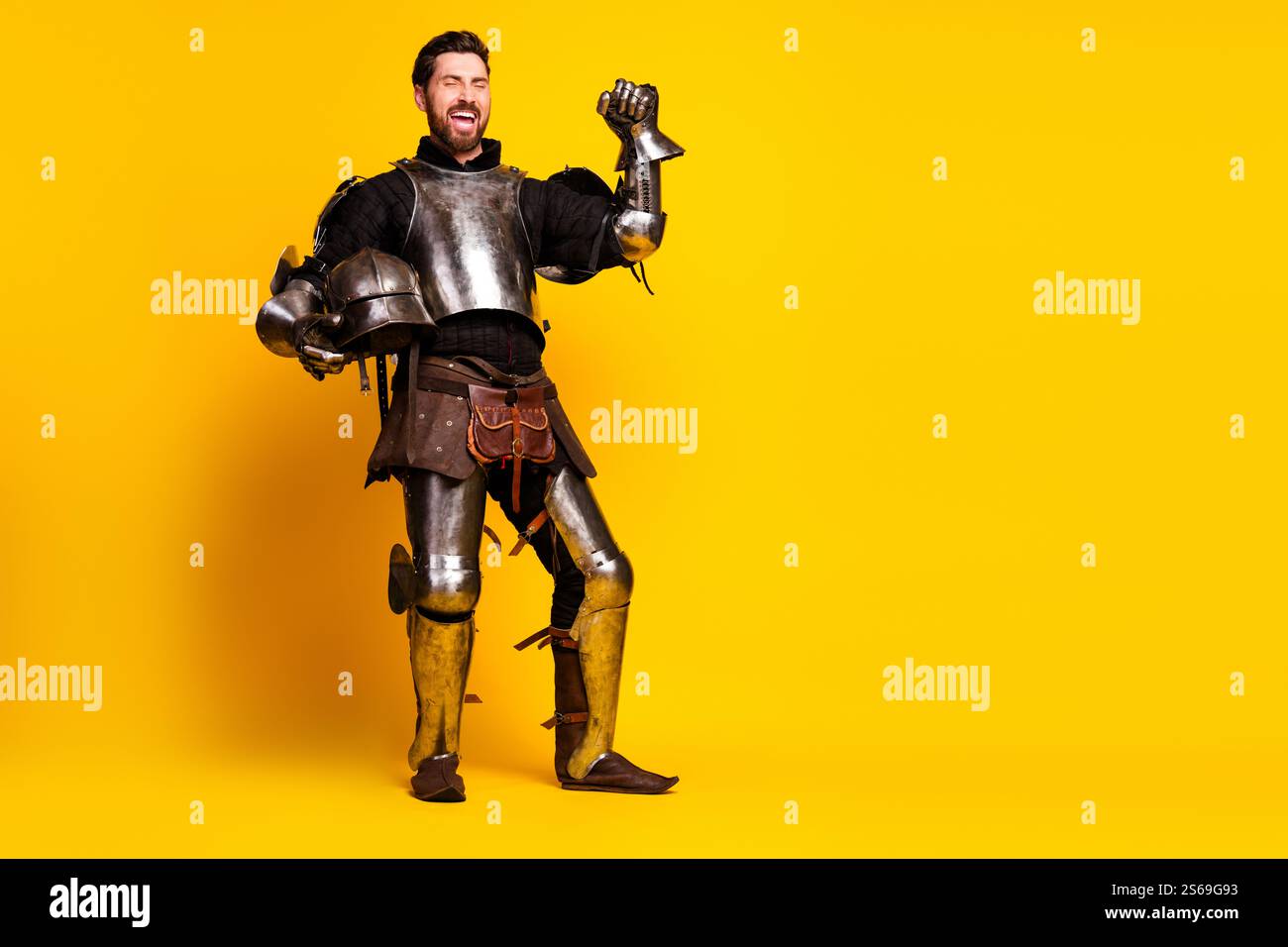 Confident knight in metallic armor poses on yellow background ...