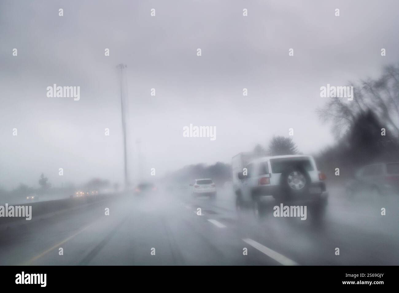 Cars driving in bad weather conditions with fog and heavy rain on ...
