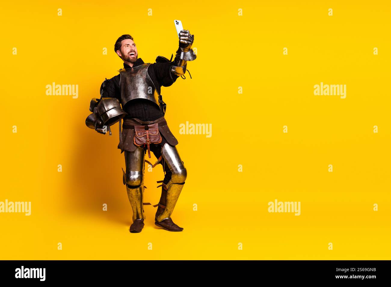 Knight in armor taking modern selfie on bright yellow background ...
