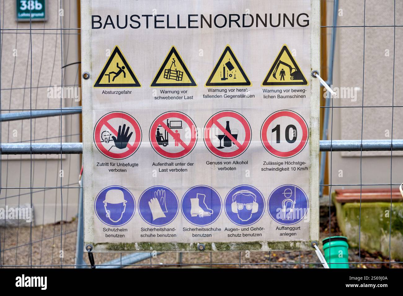 An einem Bauzaun hängt ein Plakat mit der Bauornung. In Piktogrammen ...