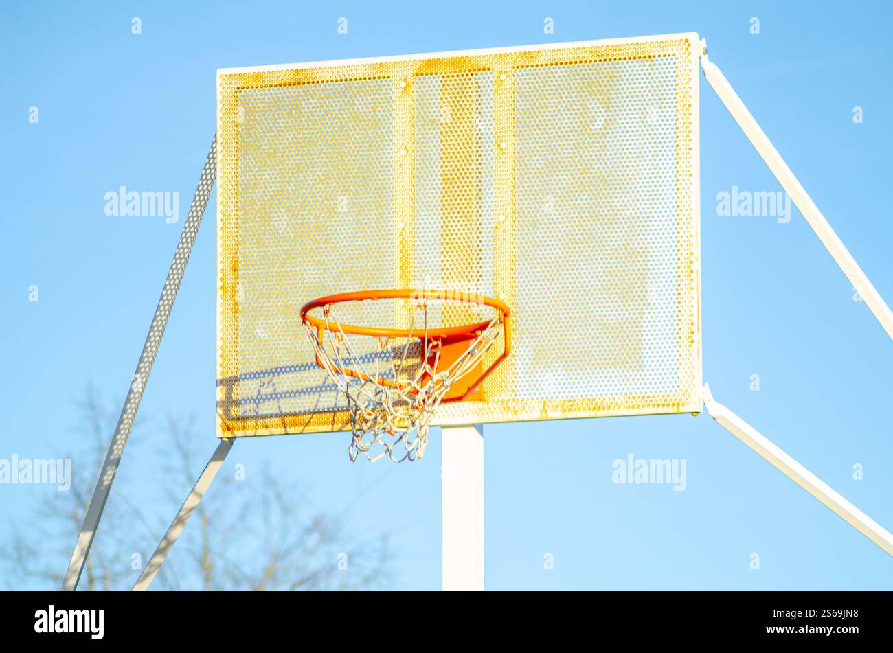 A red hoop on a white rusty metal backboard on a basketball court in a ...